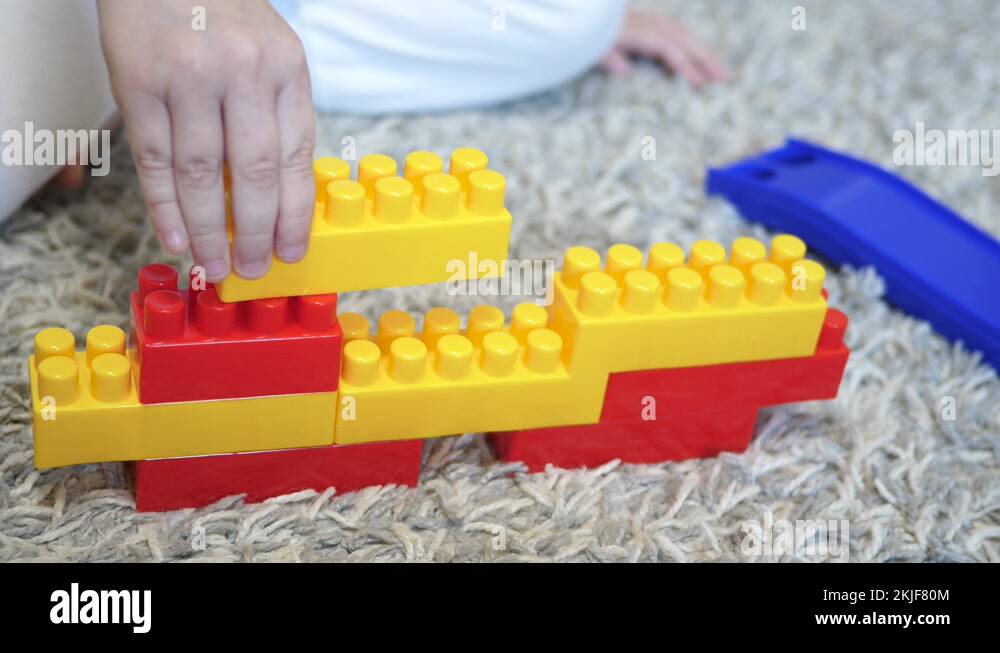 A child plays in the constructor sitting on the floor. Toy baby ...