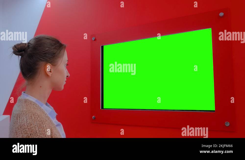 Green screen concept - woman looking at blank green display wall at ...