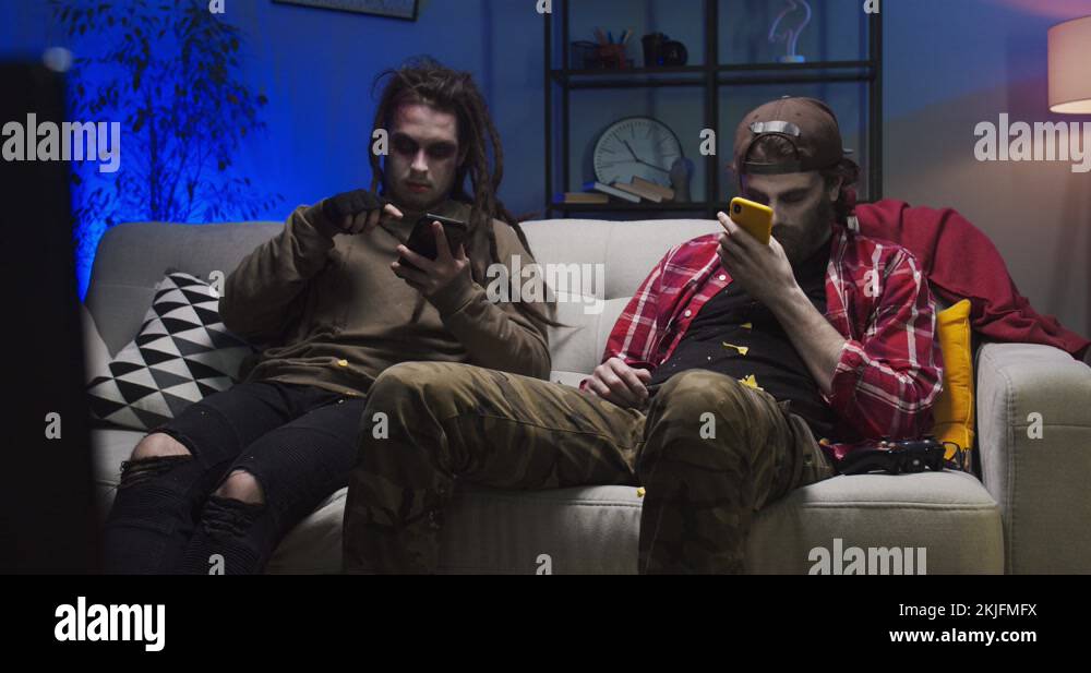 Scary male zombies sitting on the sofa at the Halloween party ...