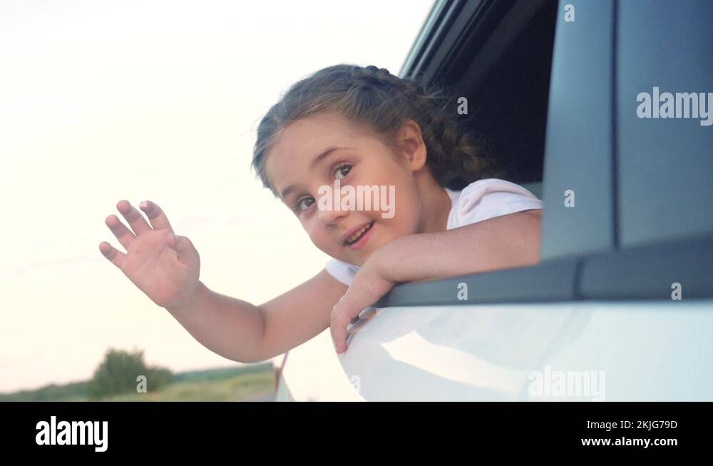 happy girl kid child smile leaned out of a car window waving hand ...