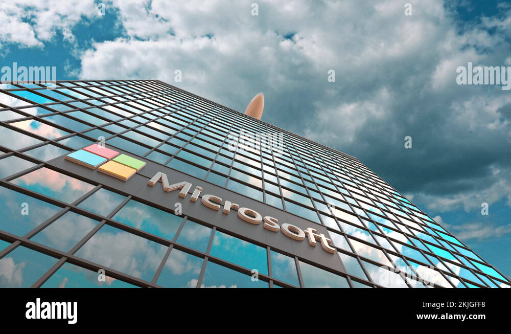Microsoft logo on a modern skyscraper reflecting clouds and flying ...