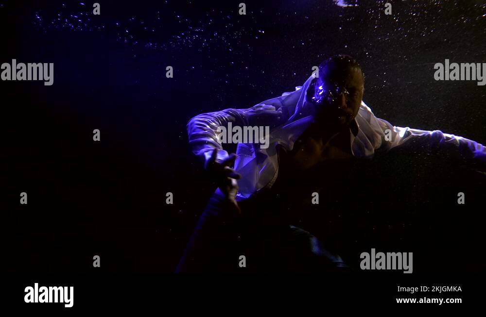black man is floating inside water of swimming pool, underwater shot ...