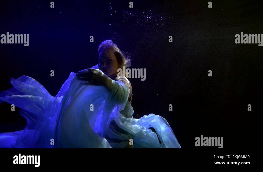 mystic woman is floating underwater and playing with white fabric ...