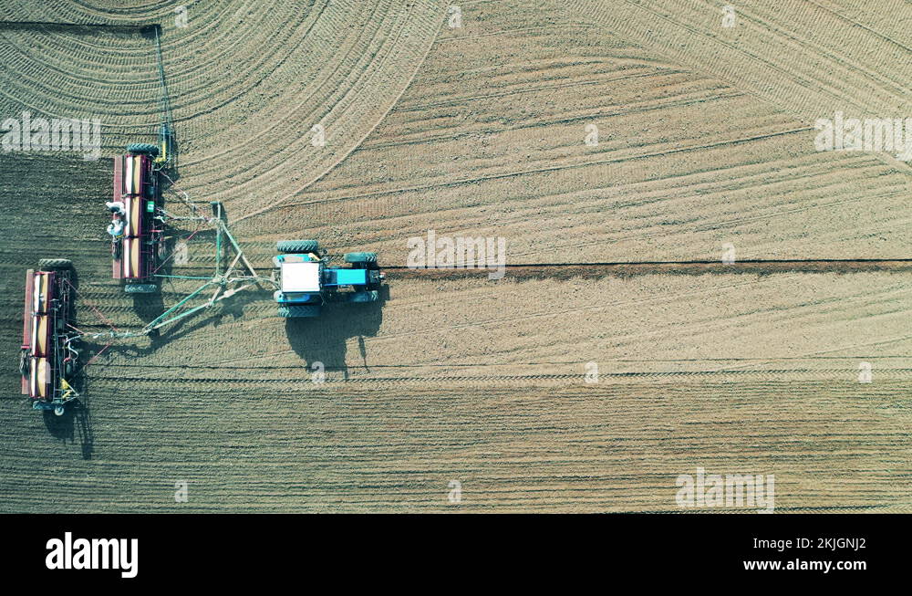 Agricultural vehicle is sowing the land in the field in a top view ...