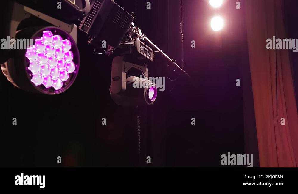 A woman illuminator hangs a spotlight on a pole with lighting fixtures ...
