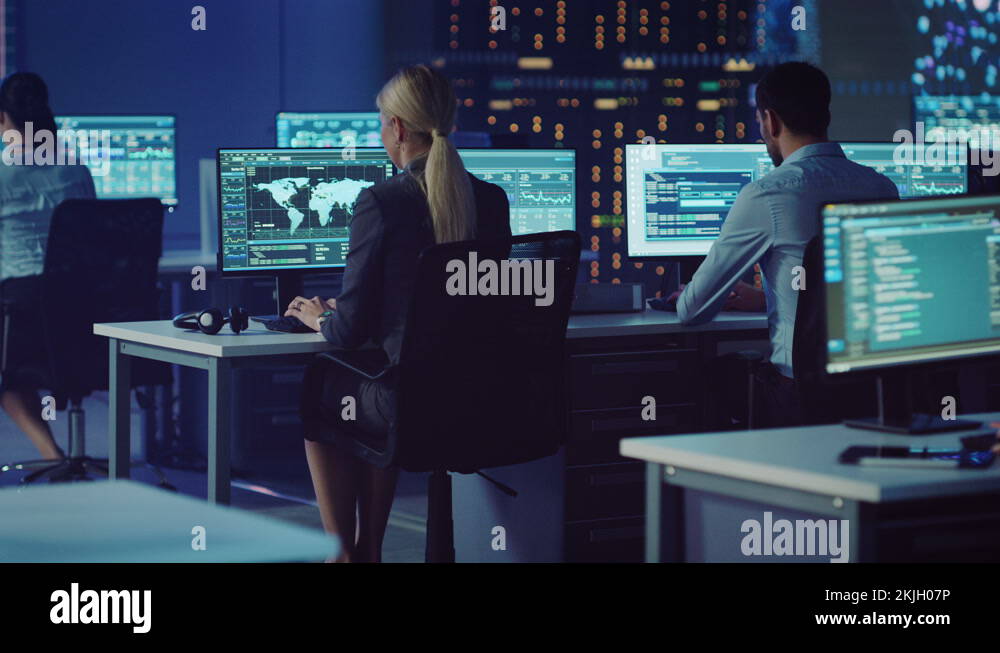 Two Computer Data Science Engineers Work behind Desk in Control Room ...