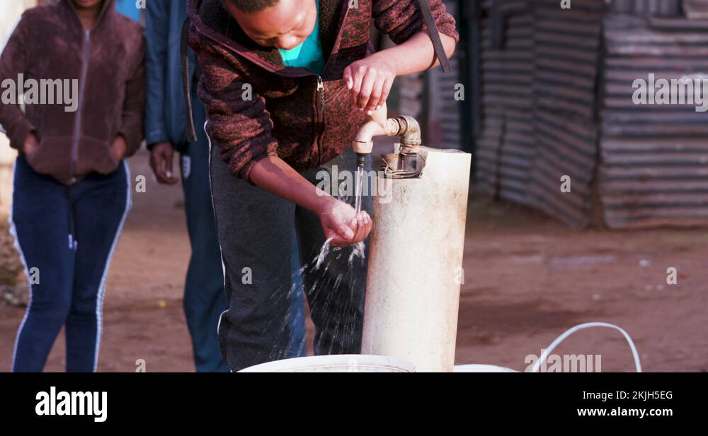 Water crisis. Young black african boy drinking water from a communal ...