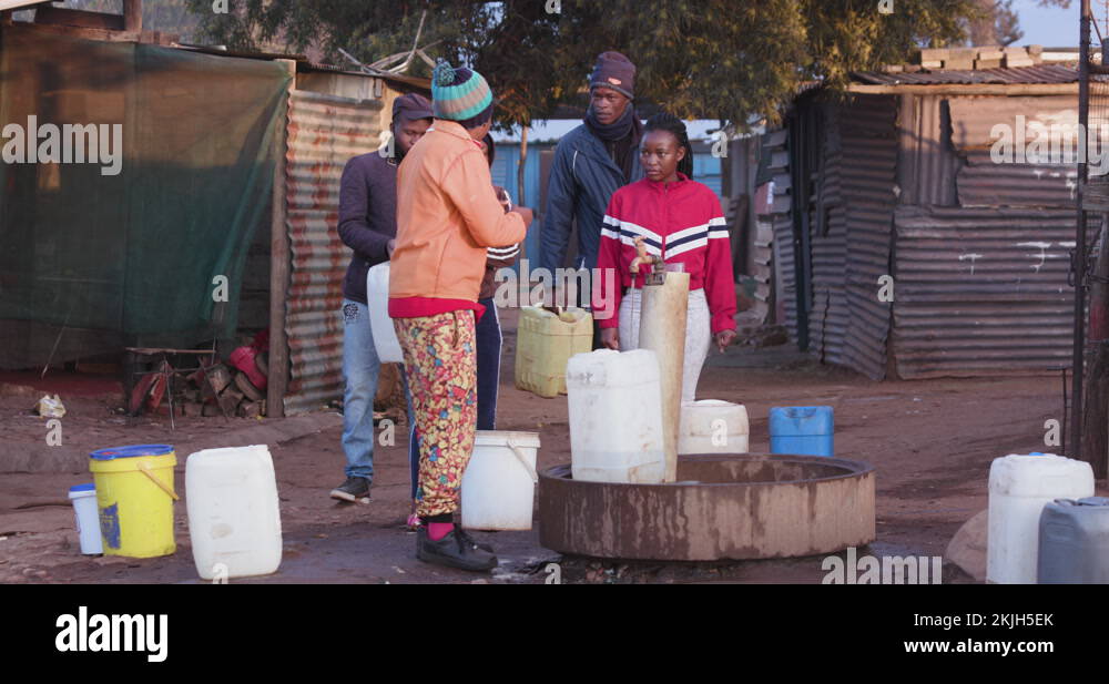 Poor Black African people getting water in containers in an informal ...