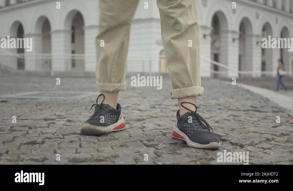 Female feet in sneakers dancing robot dance on city square ...