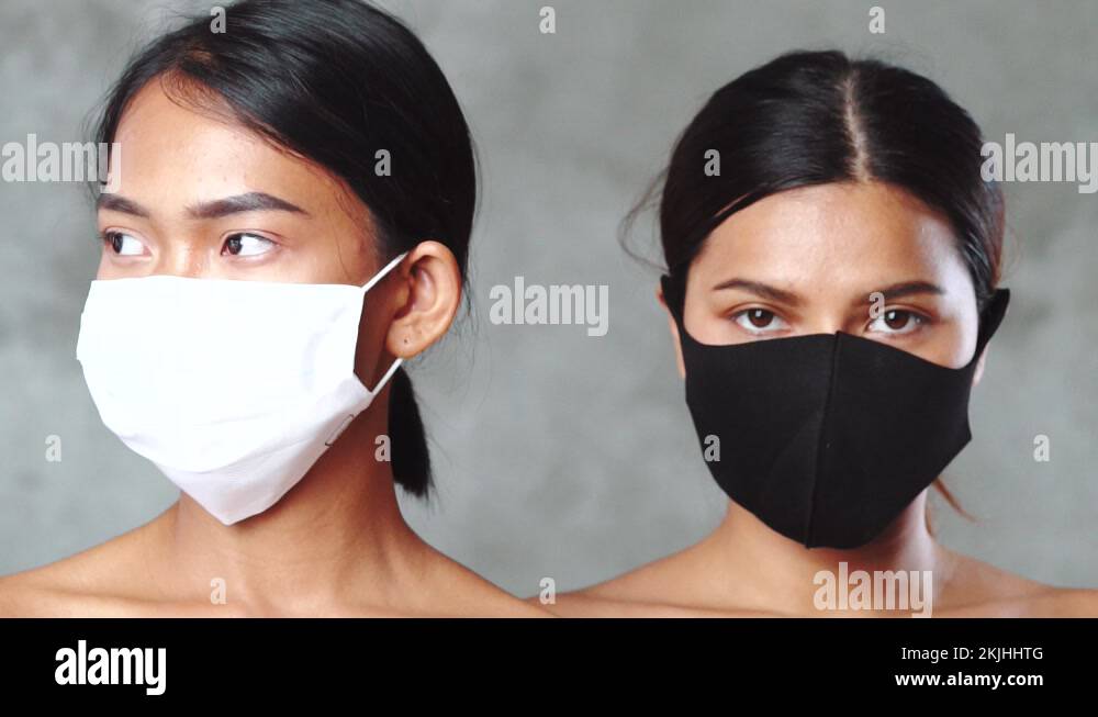 Closeup faces ot two beautiful Asian women posing in medical face mask ...
