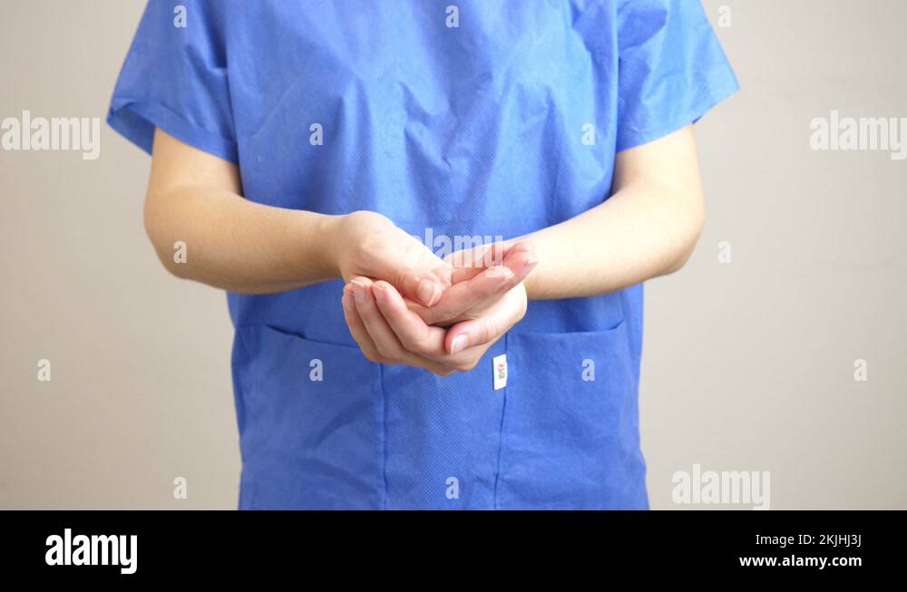 Performing hand hygiene in a blue medical suit - hand detail Stock ...