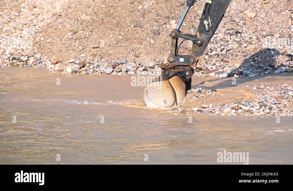 Excavator bucket close up. Excavators digging river rocks sand and ...