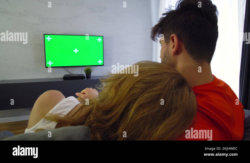 Couple in living room with green screen tv. Girl hugging boy Stock Video Footage - Alamy