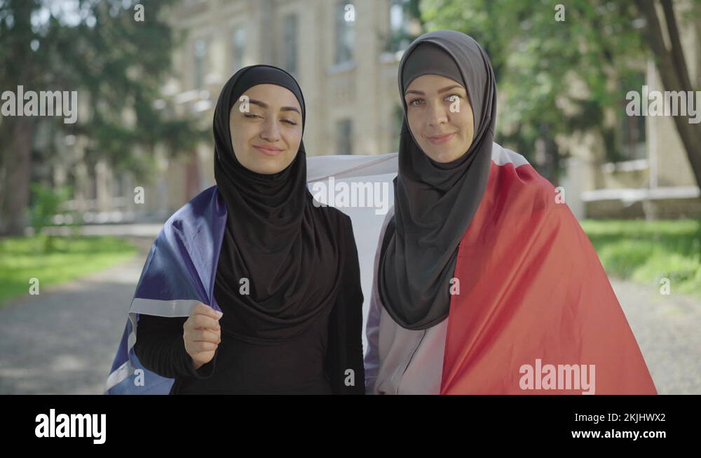 Middle shot of young Muslim women wrapped in French flag looking at ...