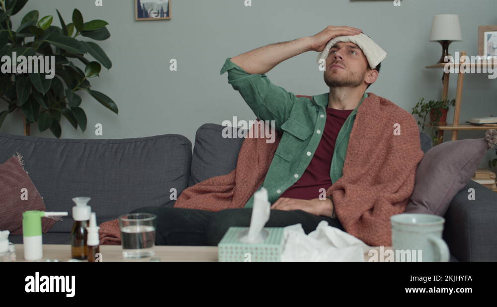 Young ill man suffering from flu and bad cough while sitting on sofa at ...
