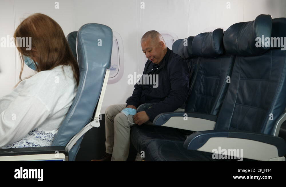 4K: Male Chinese Airplane Passenger putting on Face mask on plane ...