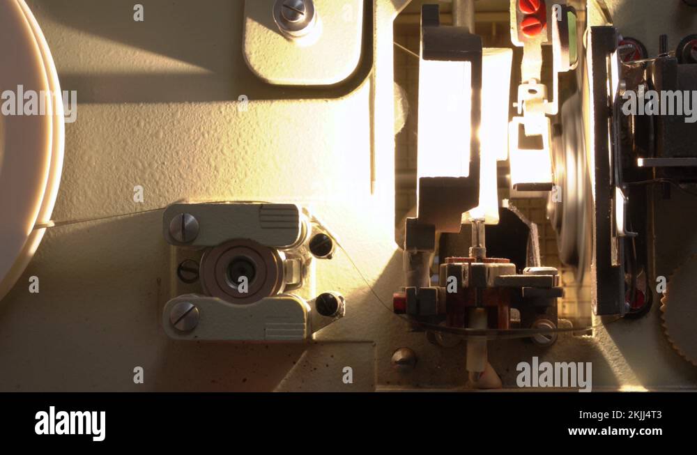 Old vintage film projector is working and showing movie, light bulb is ...