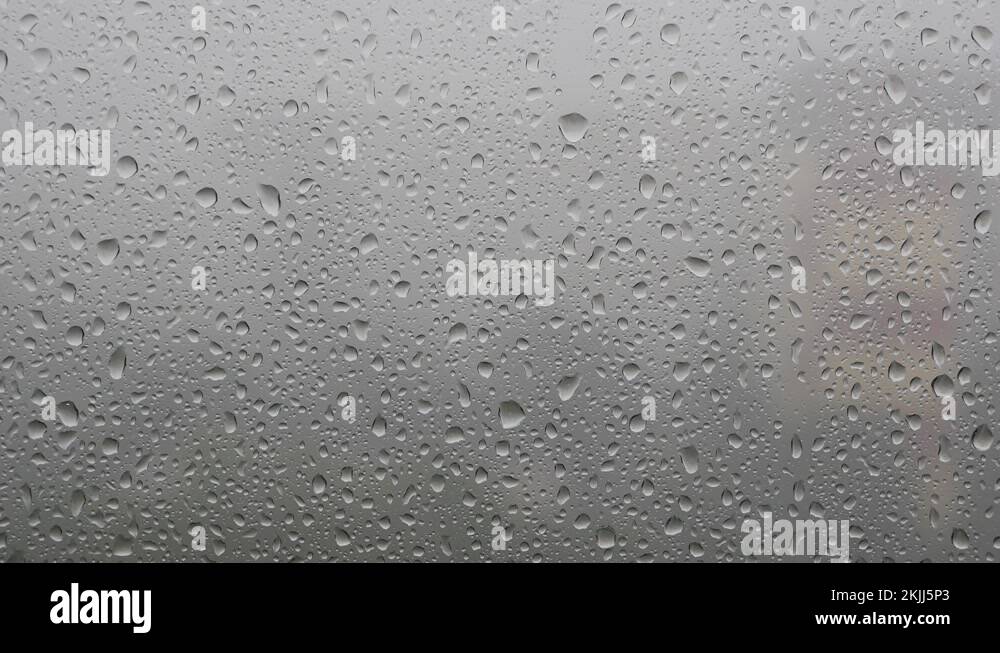 Strong rain water flushes against window glass and streaming down ...