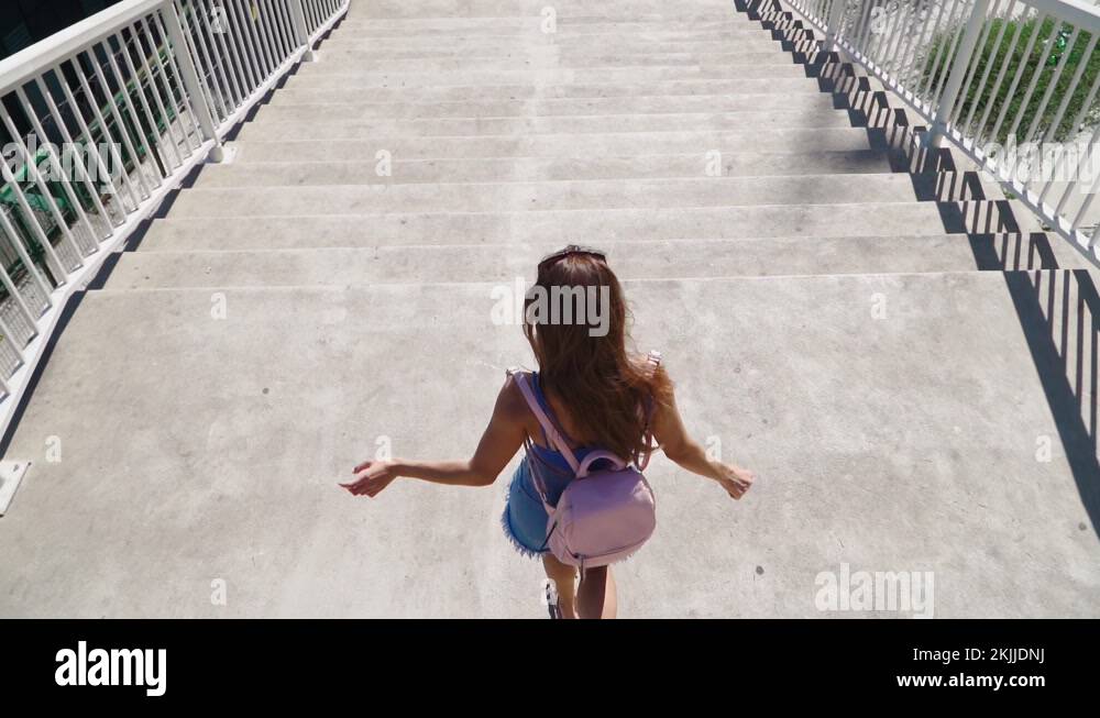 Happy Woman Coming down stairs with backpack. She wearing short shorts ...