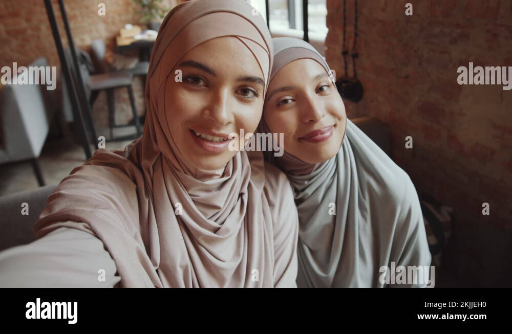 Two Pretty Women in Hijabs Posing for Camera and Taking Selfie in Cafe Stock Video Footage - Alamy