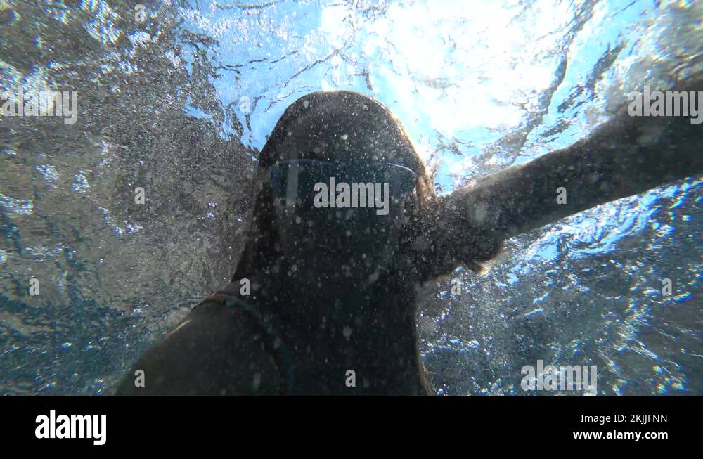 Underwater bottom view selfie of woman swimming crawl stroking with one ...