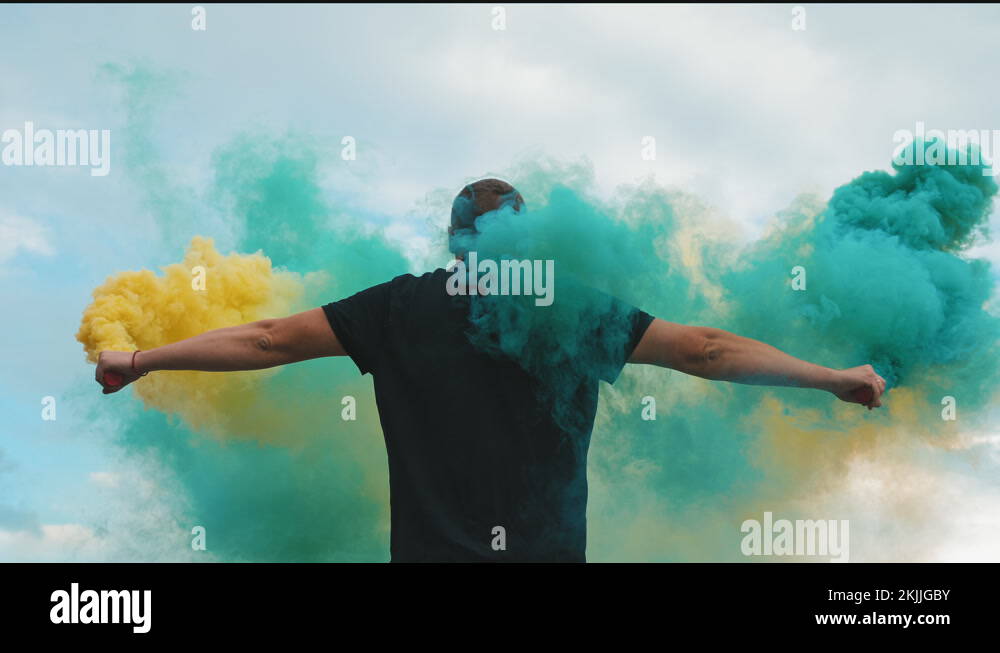 Back view of a man with a yellow and blue smoke bomb Stock Video ...