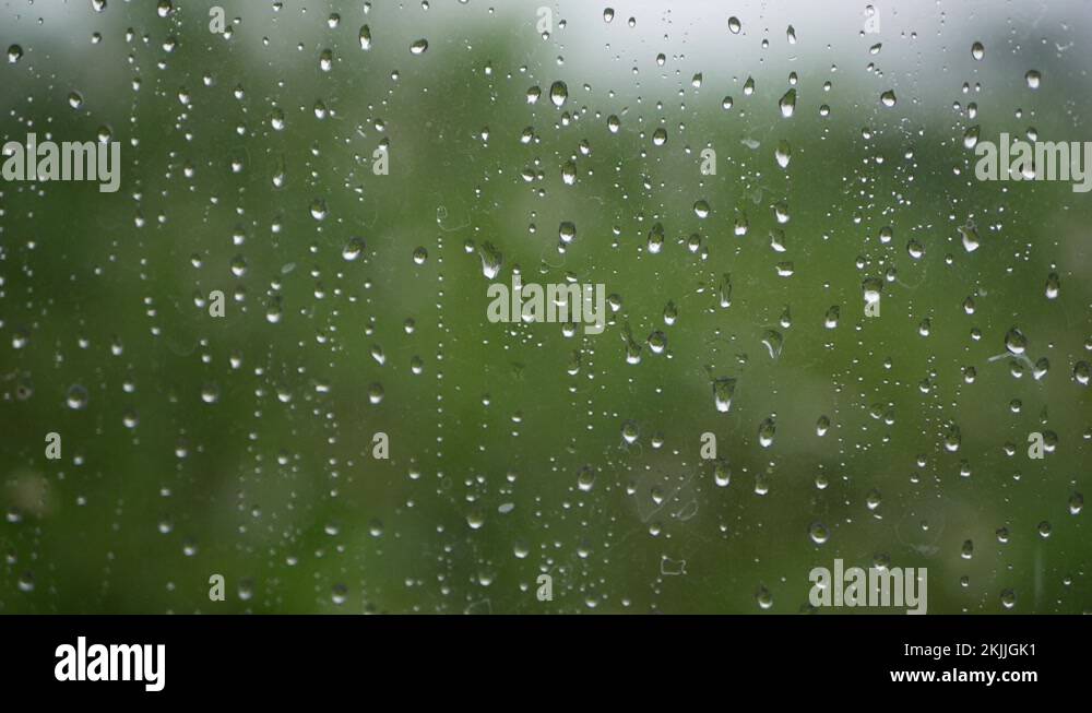 Strong rain water flushes against window glass and streaming down ...