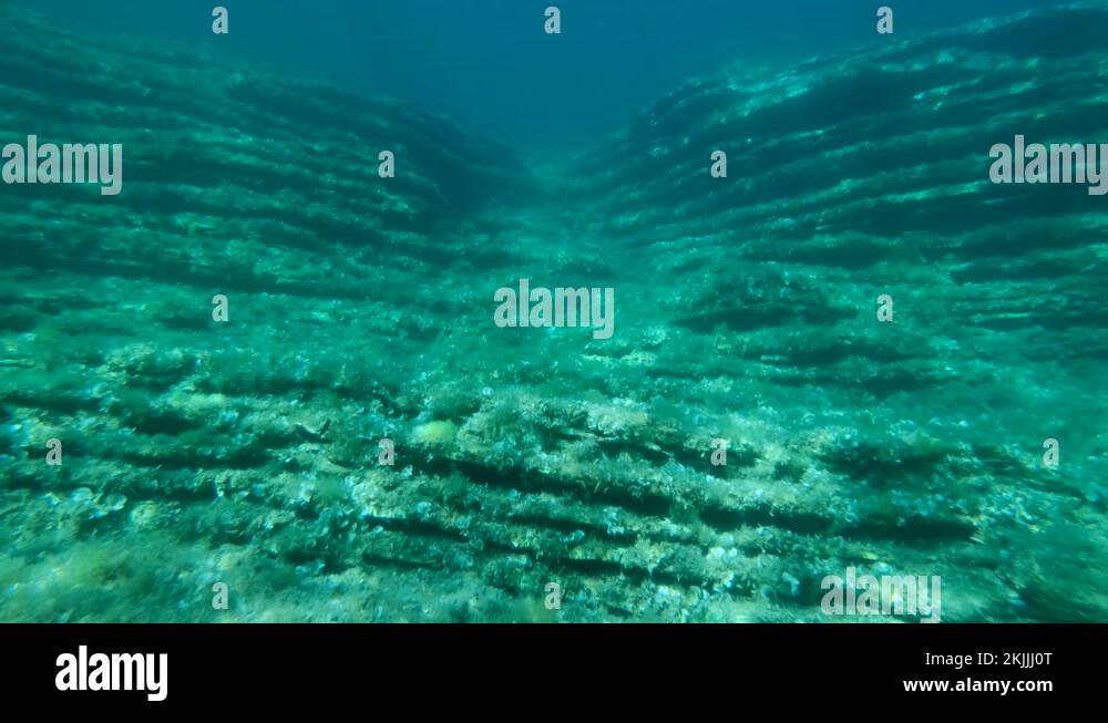 Layered rocky bottom of sedimentary rocks underwater. (4K - 60 fps ...
