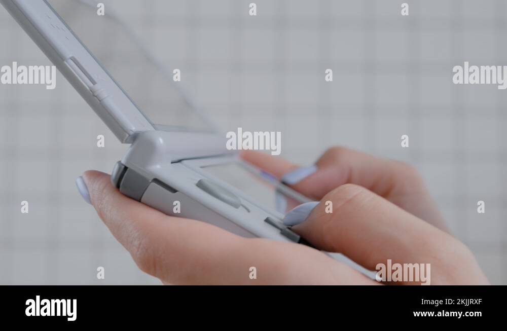 Close up side view of woman gamer using grey portable game console ...