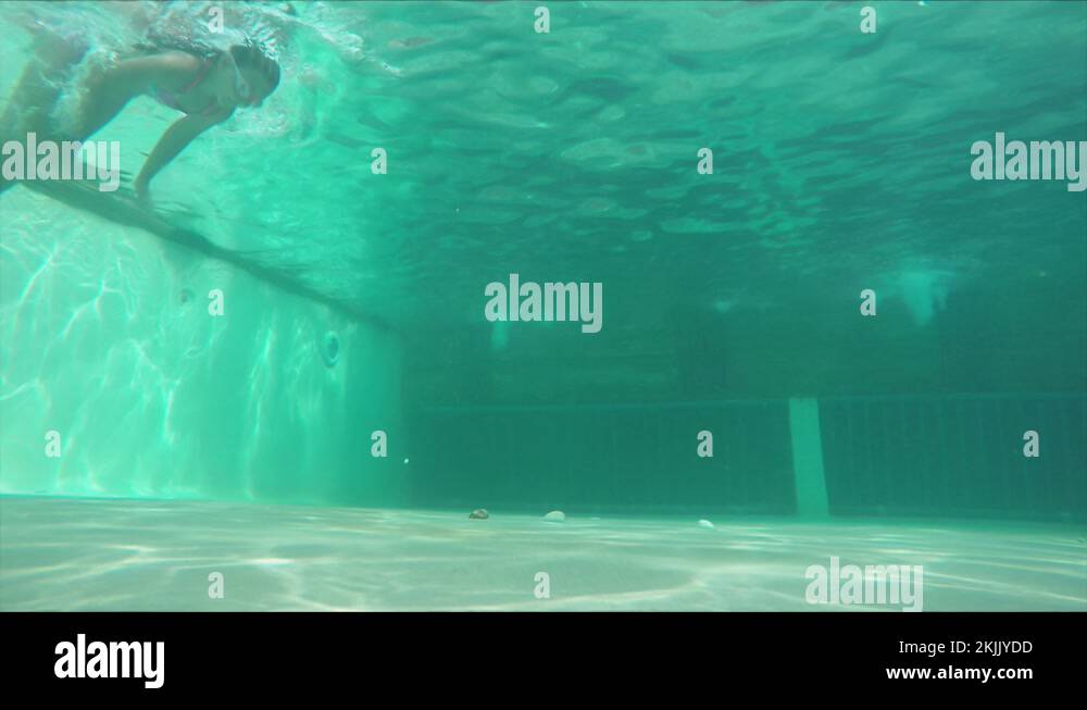A girl is swimming underwater at the bottom of the pool and collecting ...