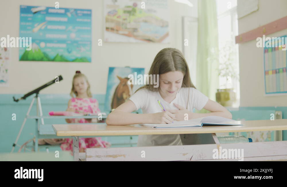 A girl student writing in an exercise notebook in a classroom of an ...