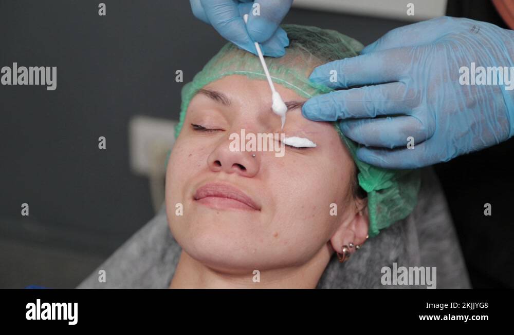 The permanent makeup artist applies an anesthetic to the lashes Stock ...