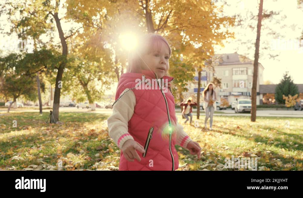 a little kid walks along path and smiles in sun. little child is ...