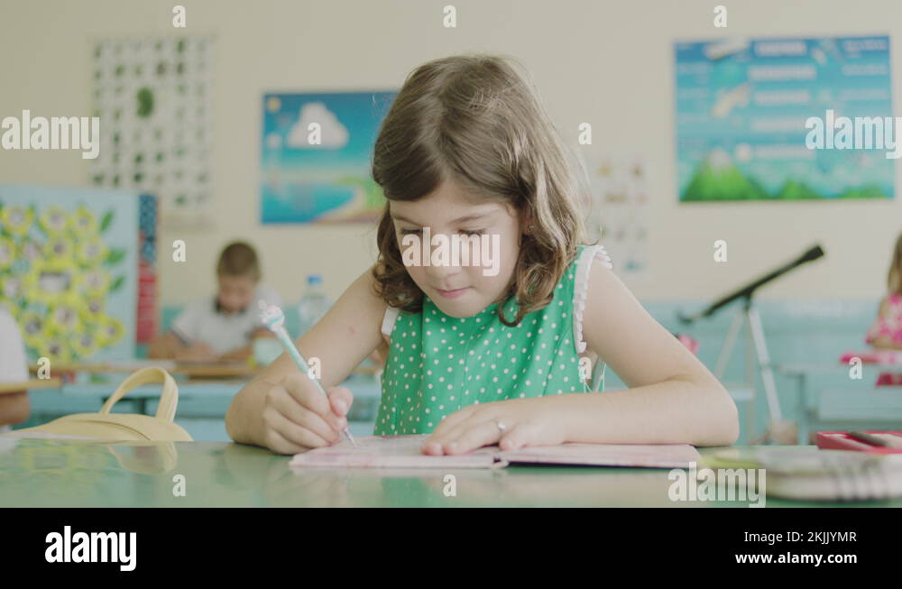 A girl student writing in an exercise notebook in a classroom of an ...