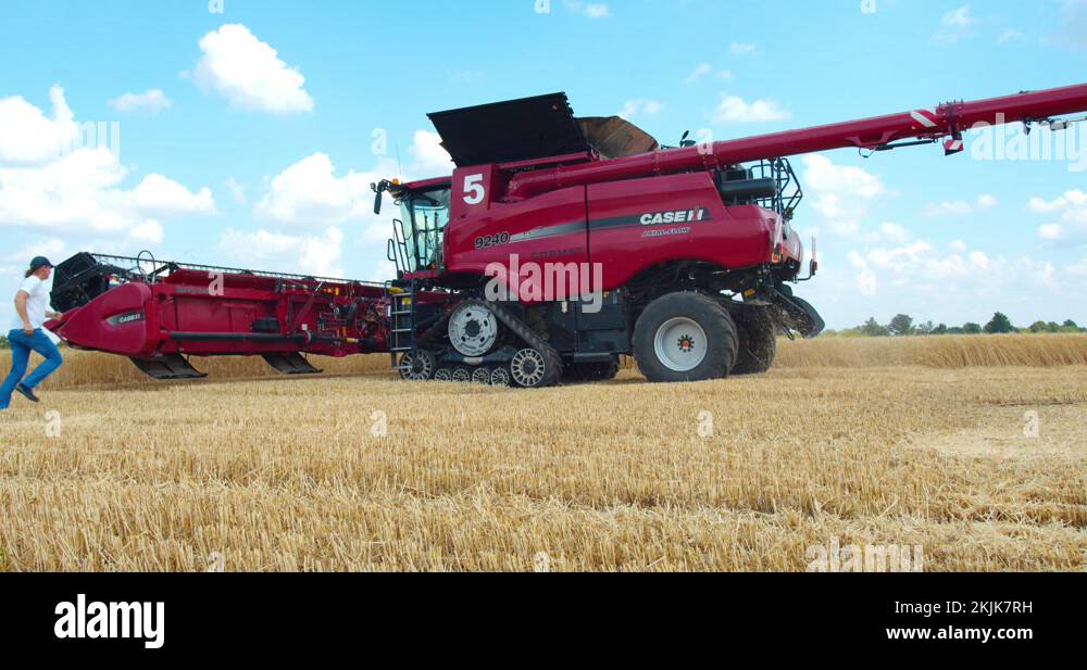 An operator is getting into a combine harvester on the wheat field, 4k ...