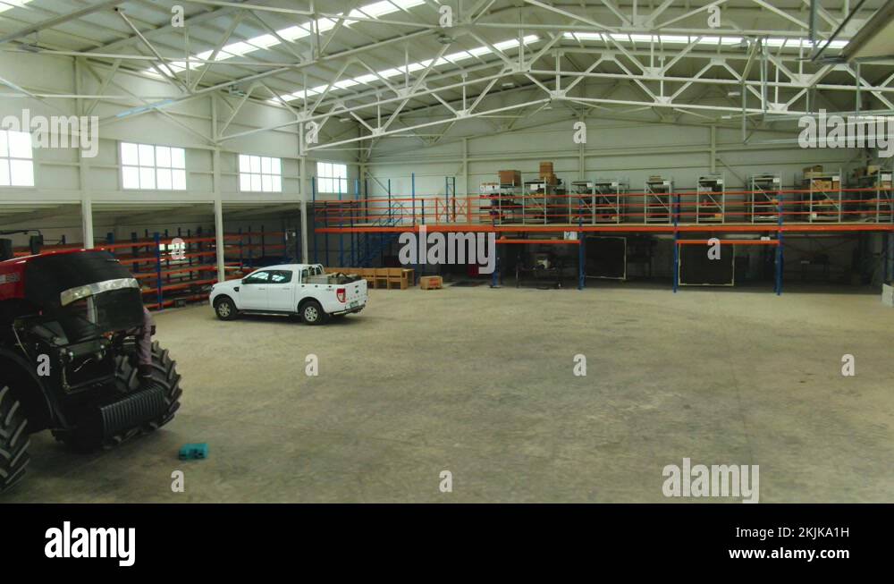 White truck and a big modern tractor in a garage for heavy machinery ...