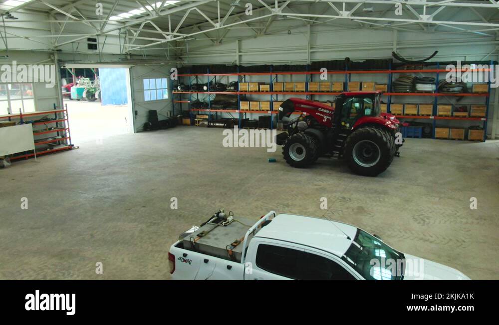 The inside of a massive hangar with a man repairing a tractor ...