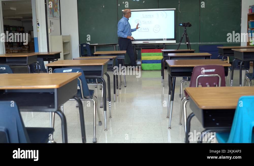Male teacher using an interactive whiteboard in an empty classroom teaching to a Stock Video ...