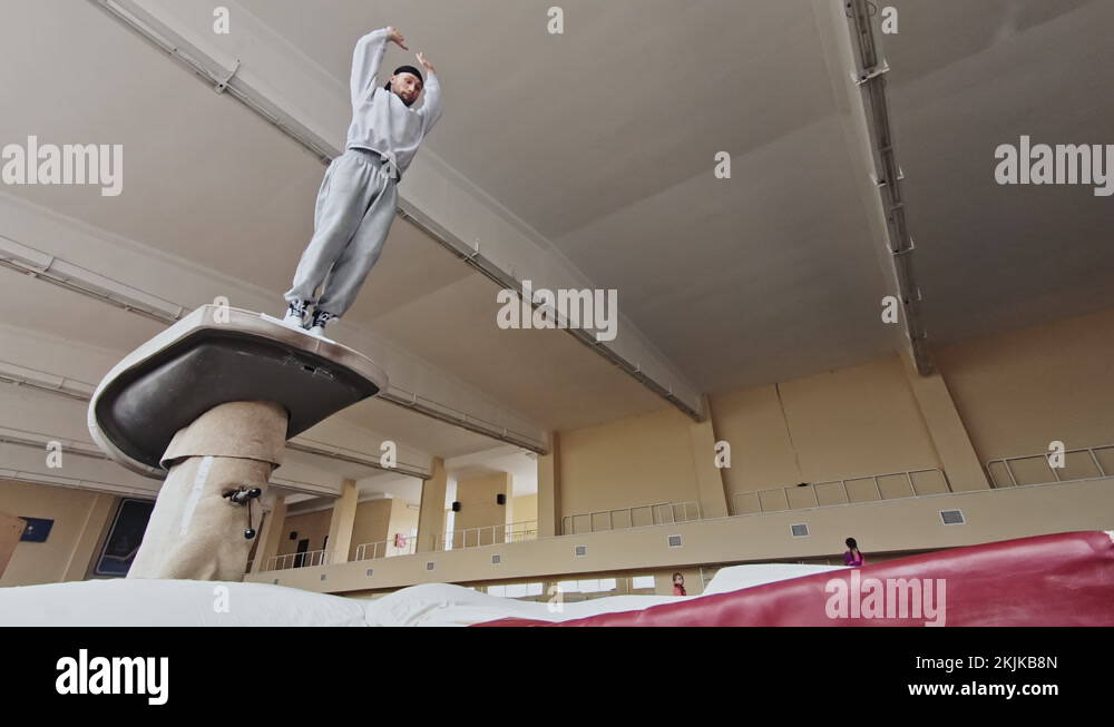 Sportsman doing front flip in gym. Strong male gymnast jumping from ...