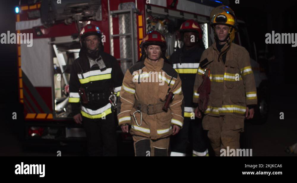 Middle plan of four firefighters approaching from fire van wearing full ...