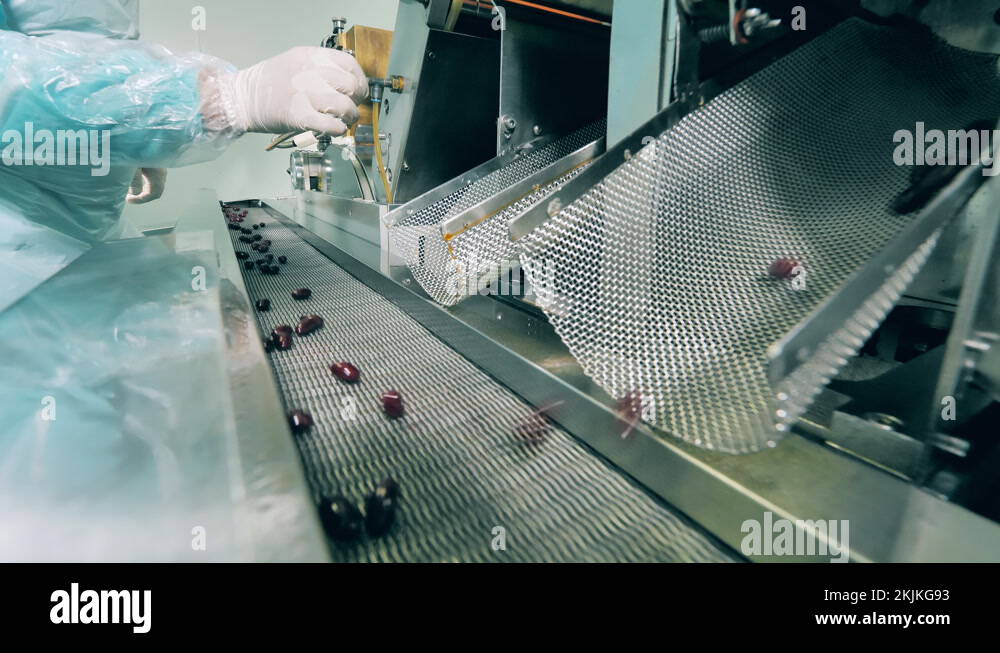 Pharmacology worker is sorting pills on the conveyorю Production of ...
