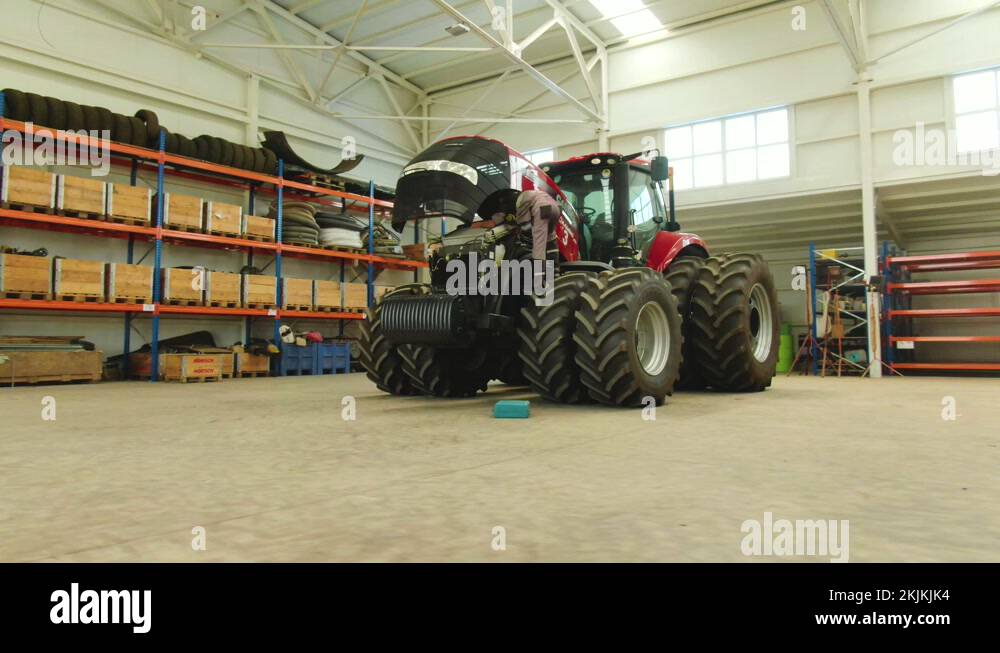 Mechanic is repairing a massive modern tractor with double tires, 4k ...