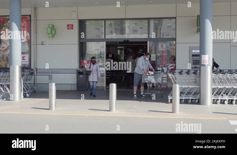 People go in and out of a supermarket with shopping carts in an urban ...