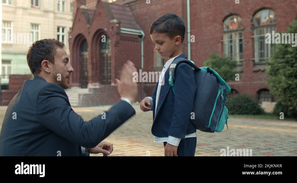 Young father in suit and teen boy doing goodbye ritual before going to ...