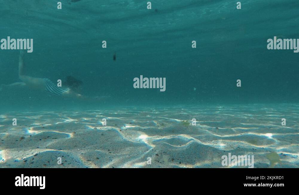 Young girl in swimsuit swims on the bottom of the sea. Slow motion ...