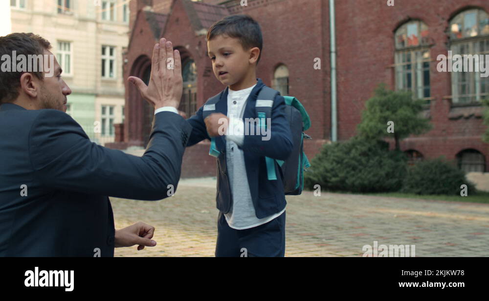 Crop view of dad in suit and cute boy doing goodbye ritual before going ...