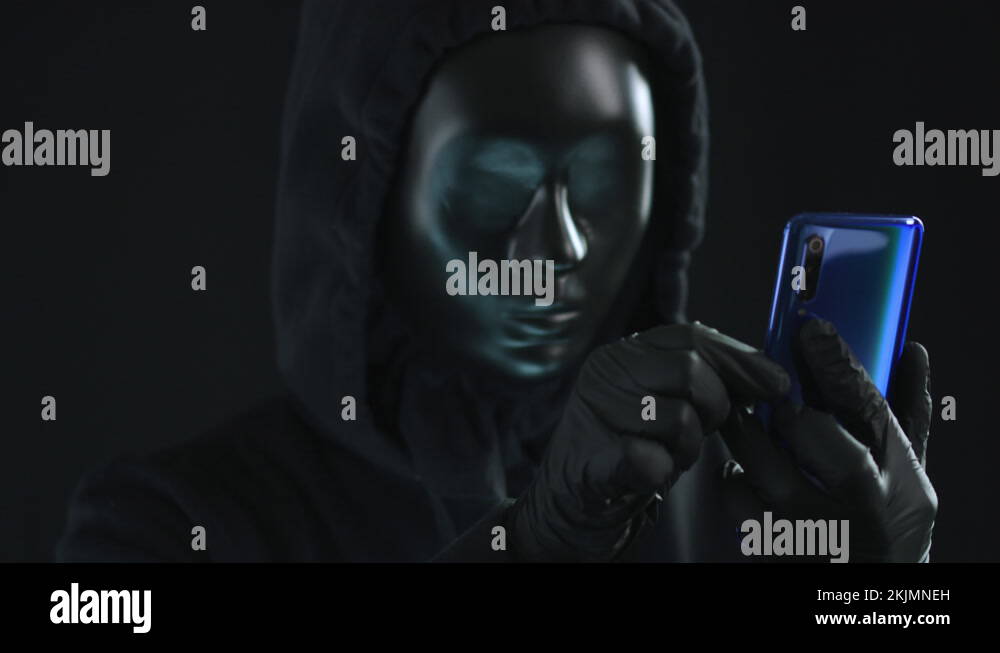 Hacker wearing black mask pulls HACKING tab from a smartphone Stock ...