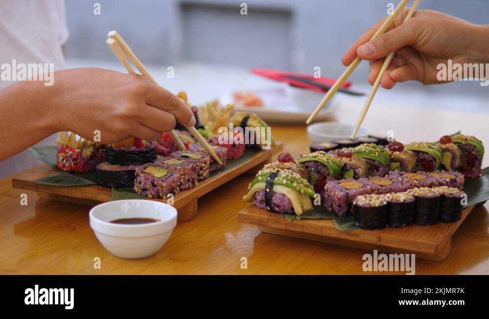 Two people having sushi lunch. Side view of hands using chopsticks to eat sushi Stock Video ...