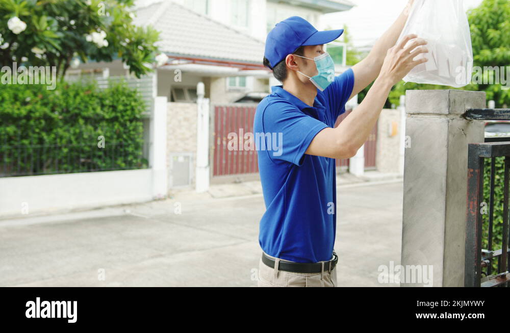 Young delivery man wear face mask handling food box for end to customer ...