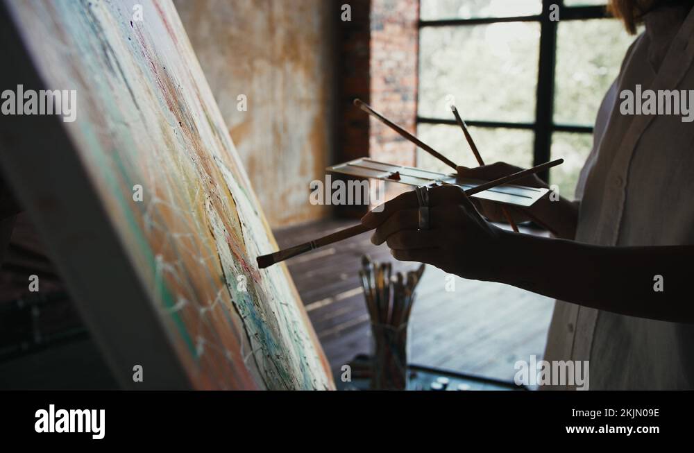 Unrecognizable female artist is painting on canvas in modern art style ...